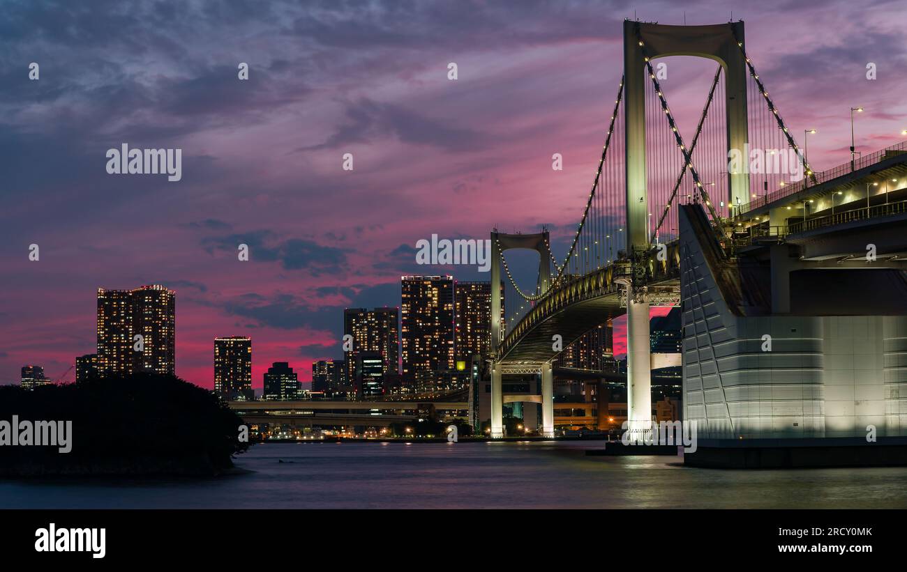 A purple dusk sky above the skyscrapers of Tokyo and Rainbow Bridge ...