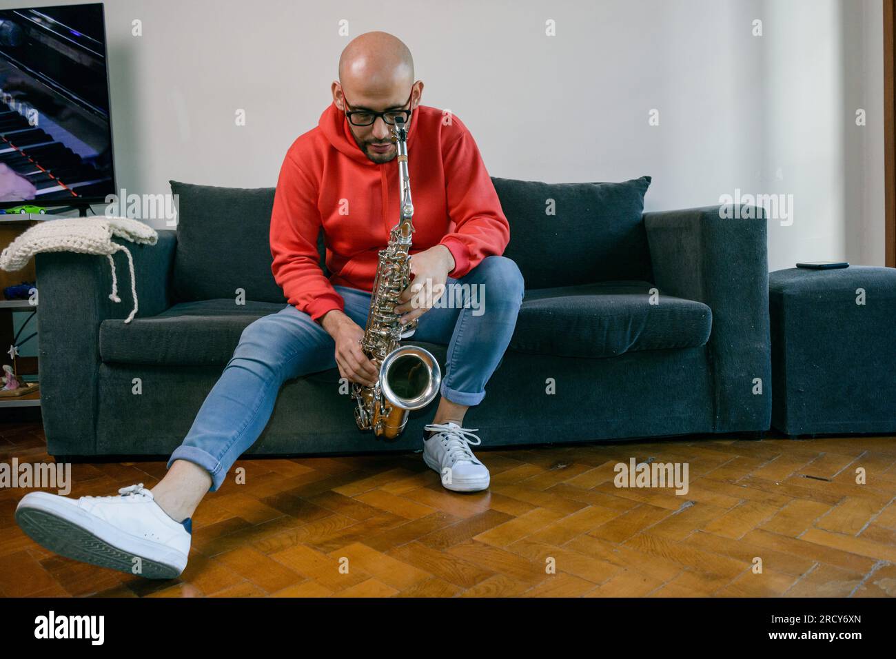 latin man musician dressed in red, at home sitting on the sofa in the ...