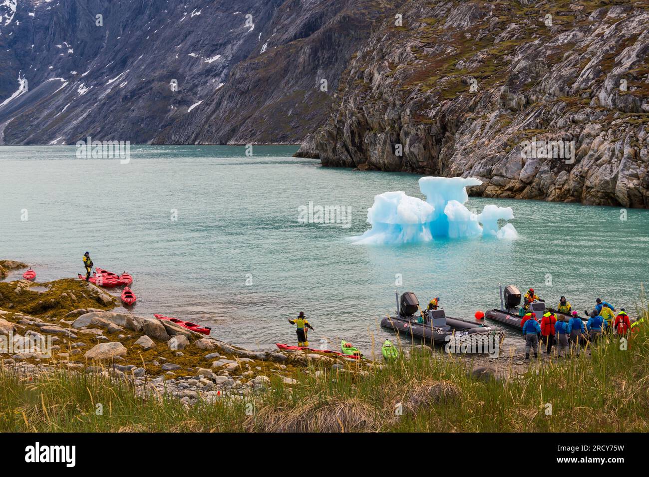 Tourists and expedition team with zodiacs and kayaks in bay with ...