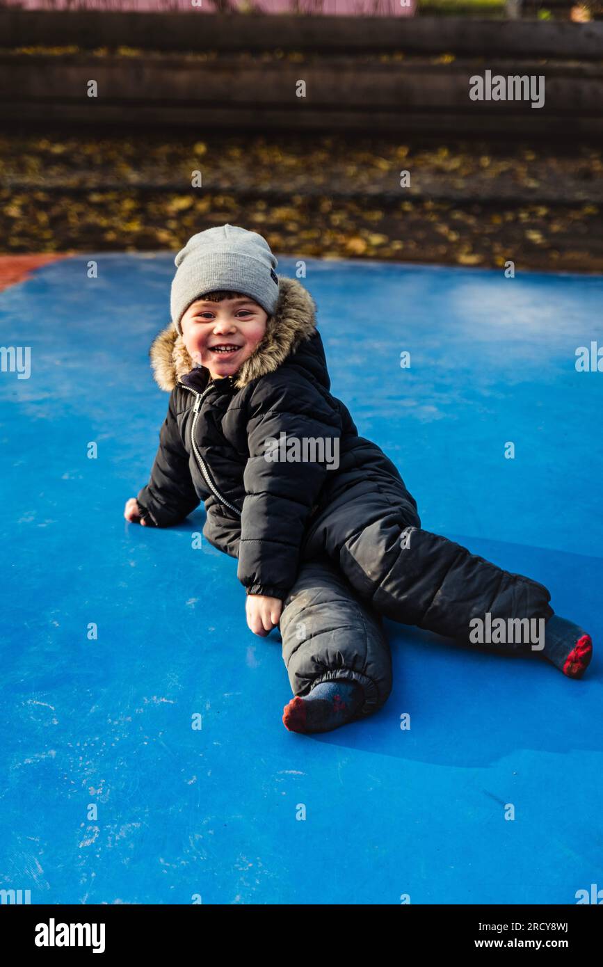 Smiling kid sitting on a blue trampoline. Child with a tired look ...