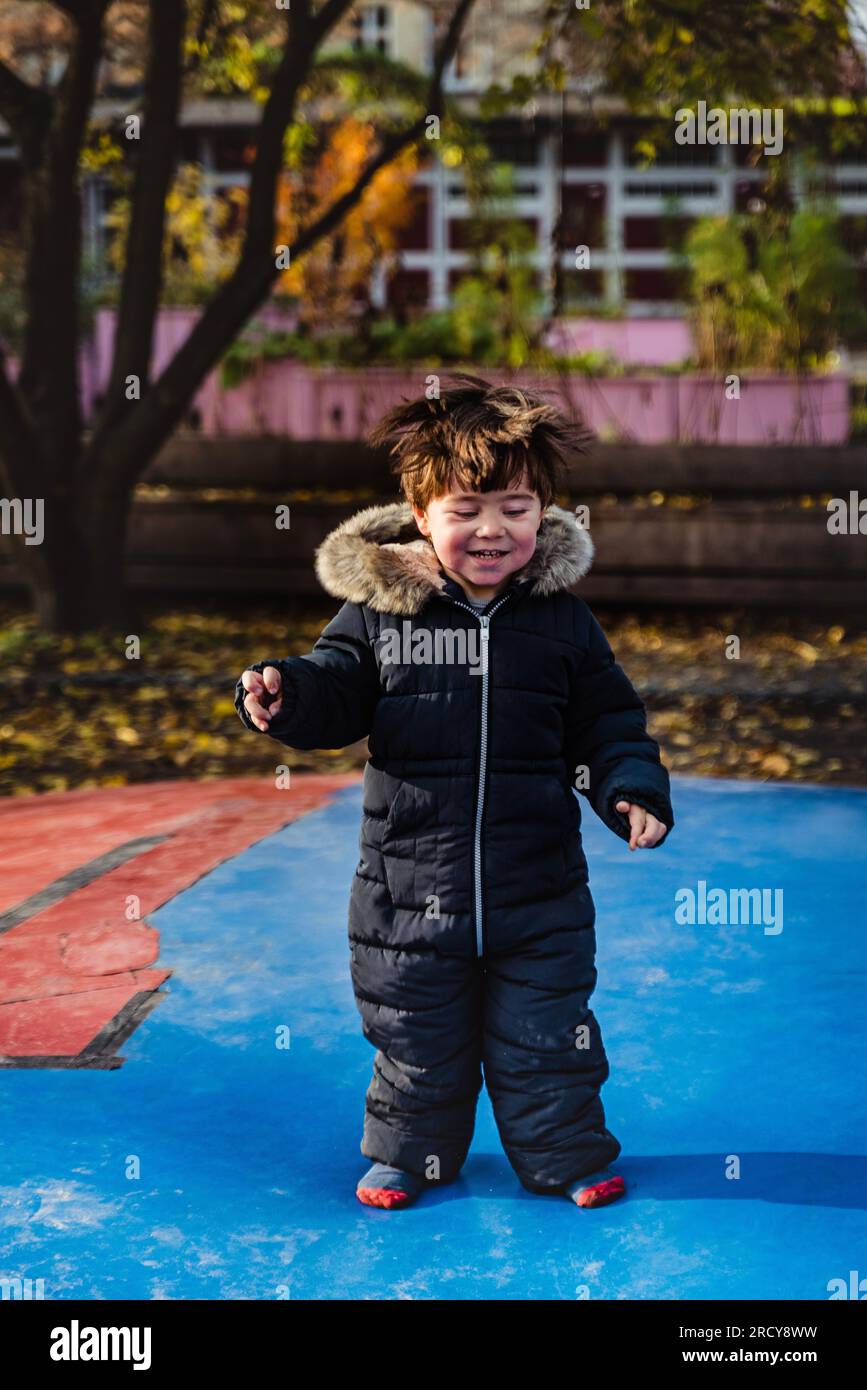 Child standing on a trampoline is laughing and having fun in a ...