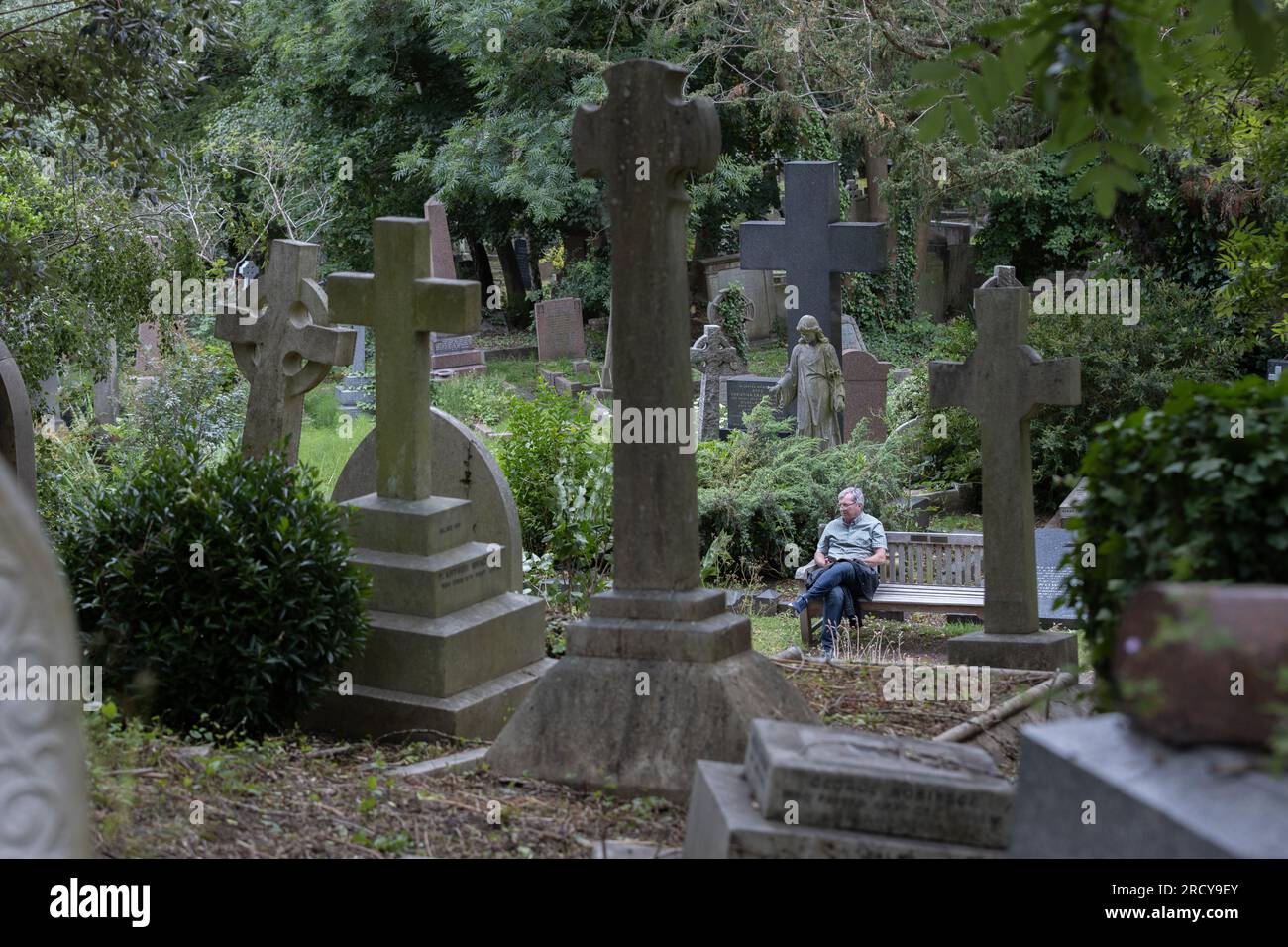 London, UK- 16 July 2023: A visitor sits among the graves, Highgate ...