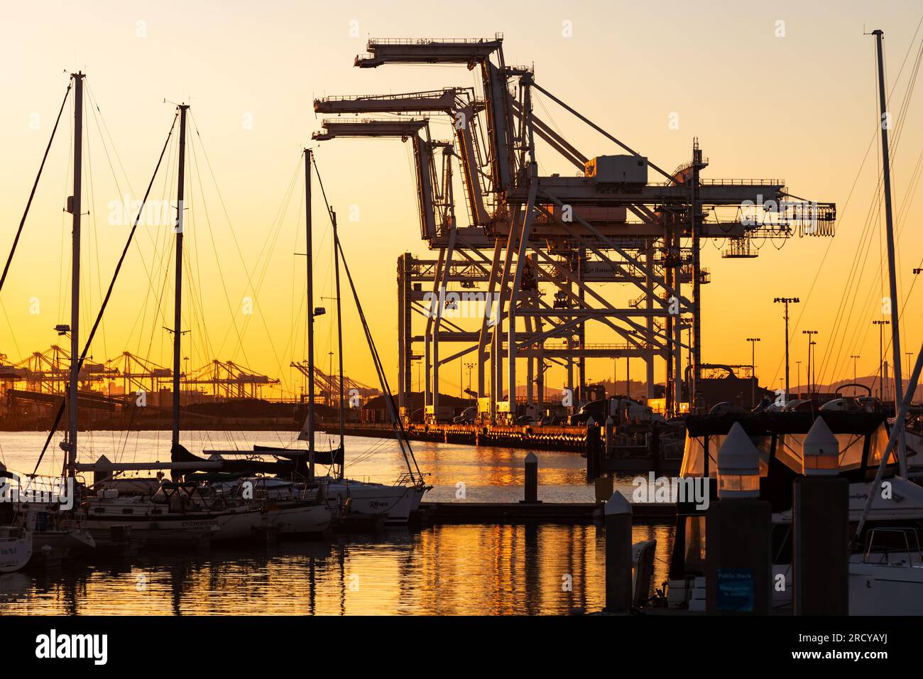 Golden sunset sun lights up the loading cranes of The Port and yachts ...