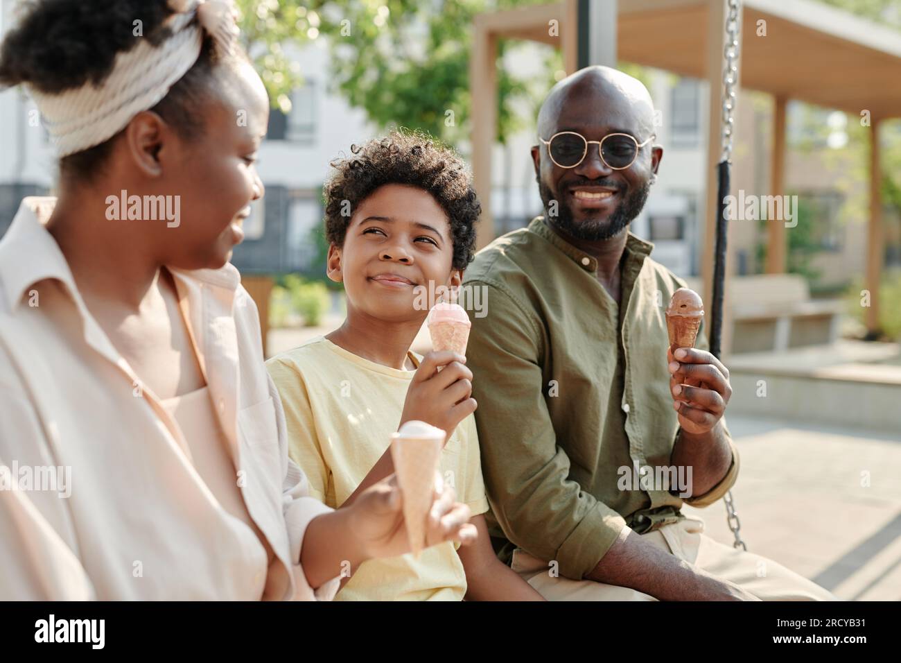 Happy African American family eating ice cream together outdoors while ...