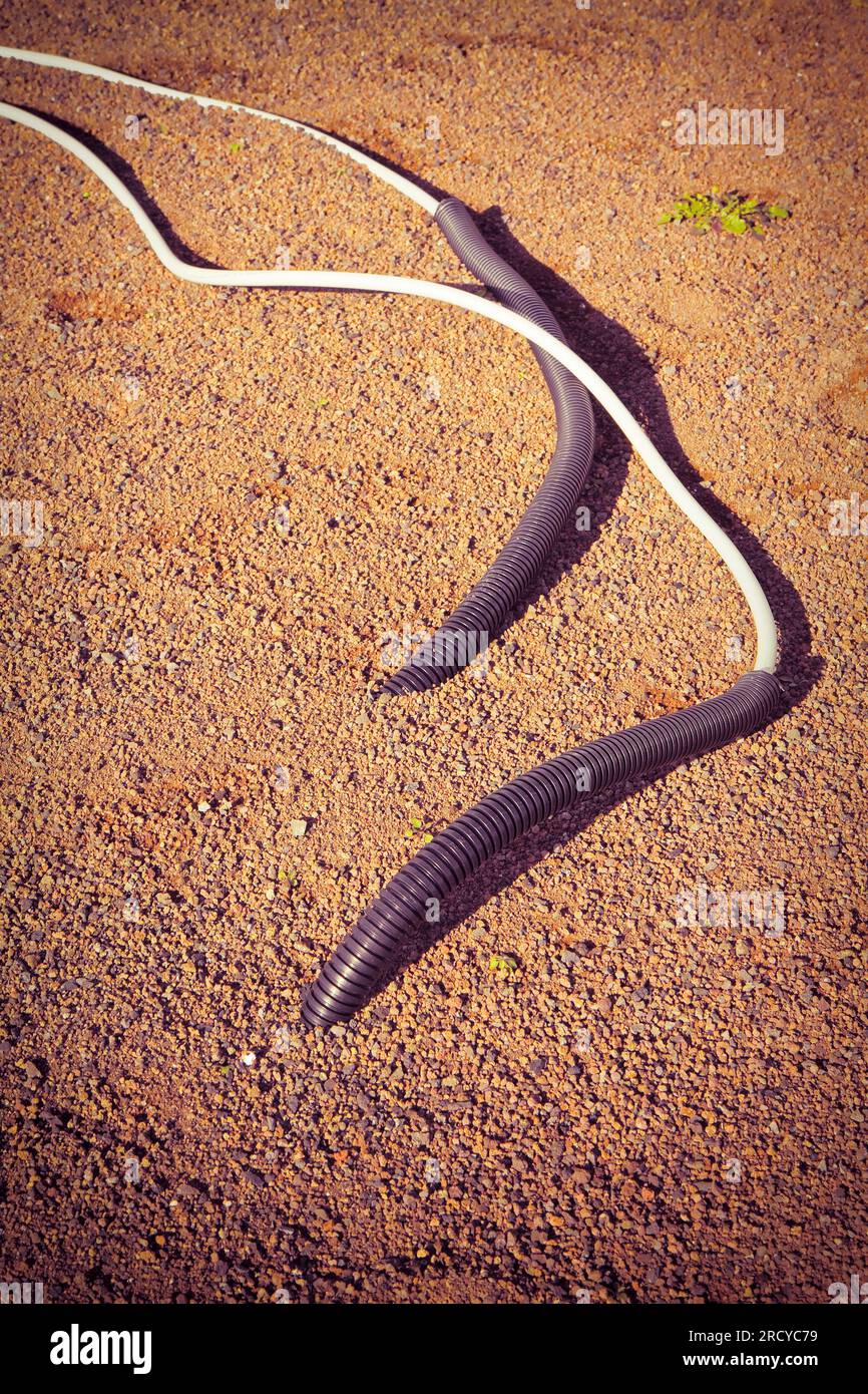 Corrugated pipe with cable coming out from the ground Stock Photo - Alamy