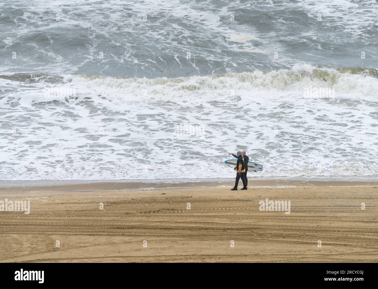 A surfer and security guard by rough seas on a stormy summer day at ...