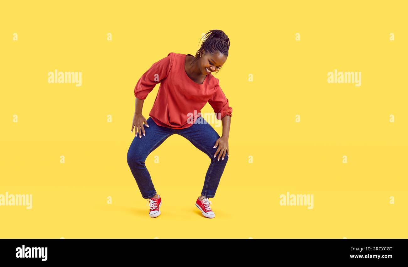 Happy beautiful young black female dancer dancing against a yellow ...