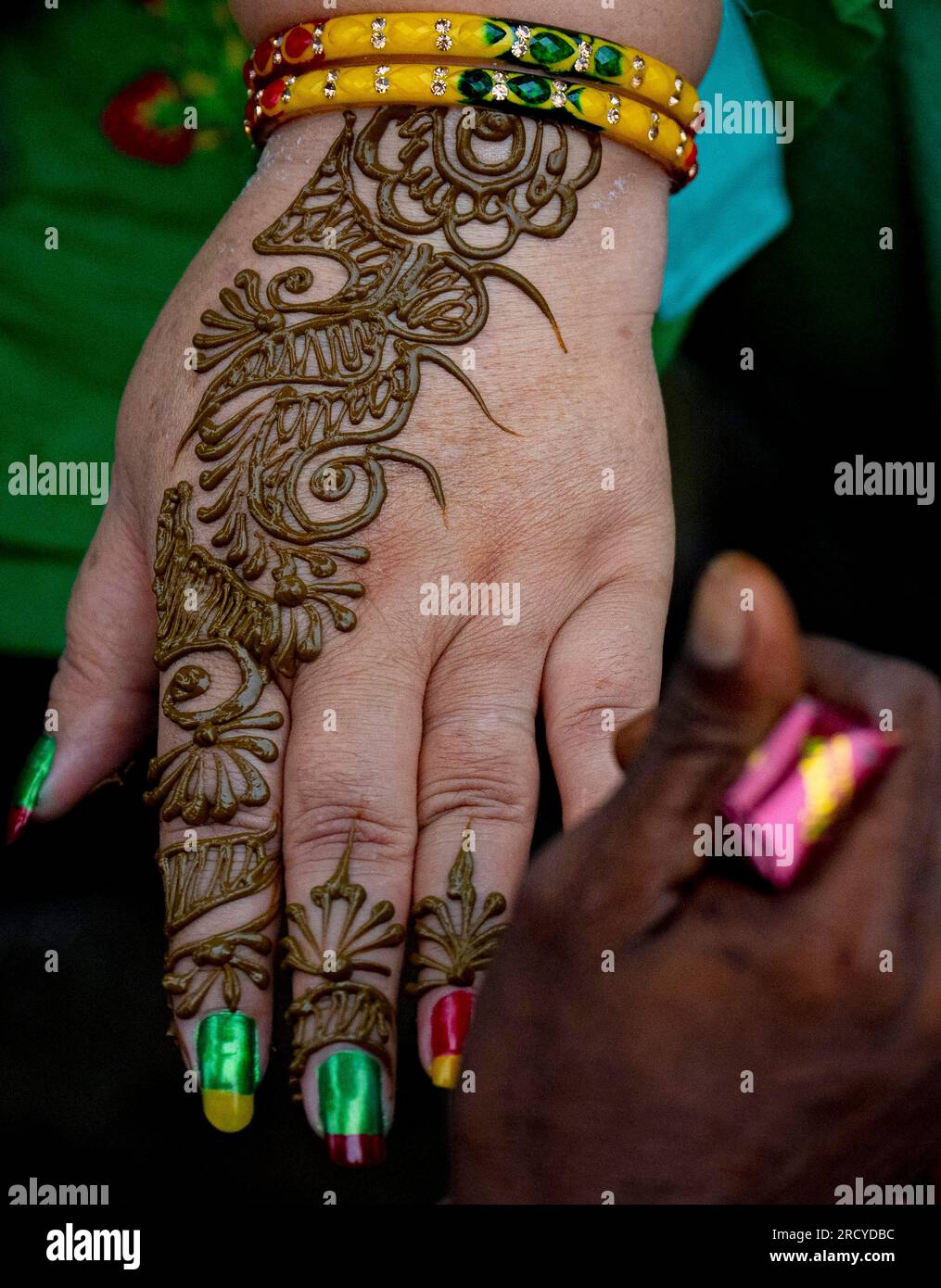 A woman gets her hand decorated with henna as part of festivities ...