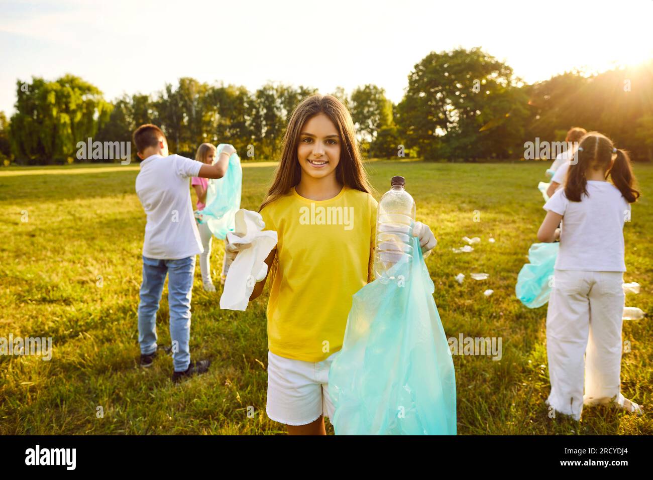 Child girl and children volunteers cleaning plastic trash from grass in ...