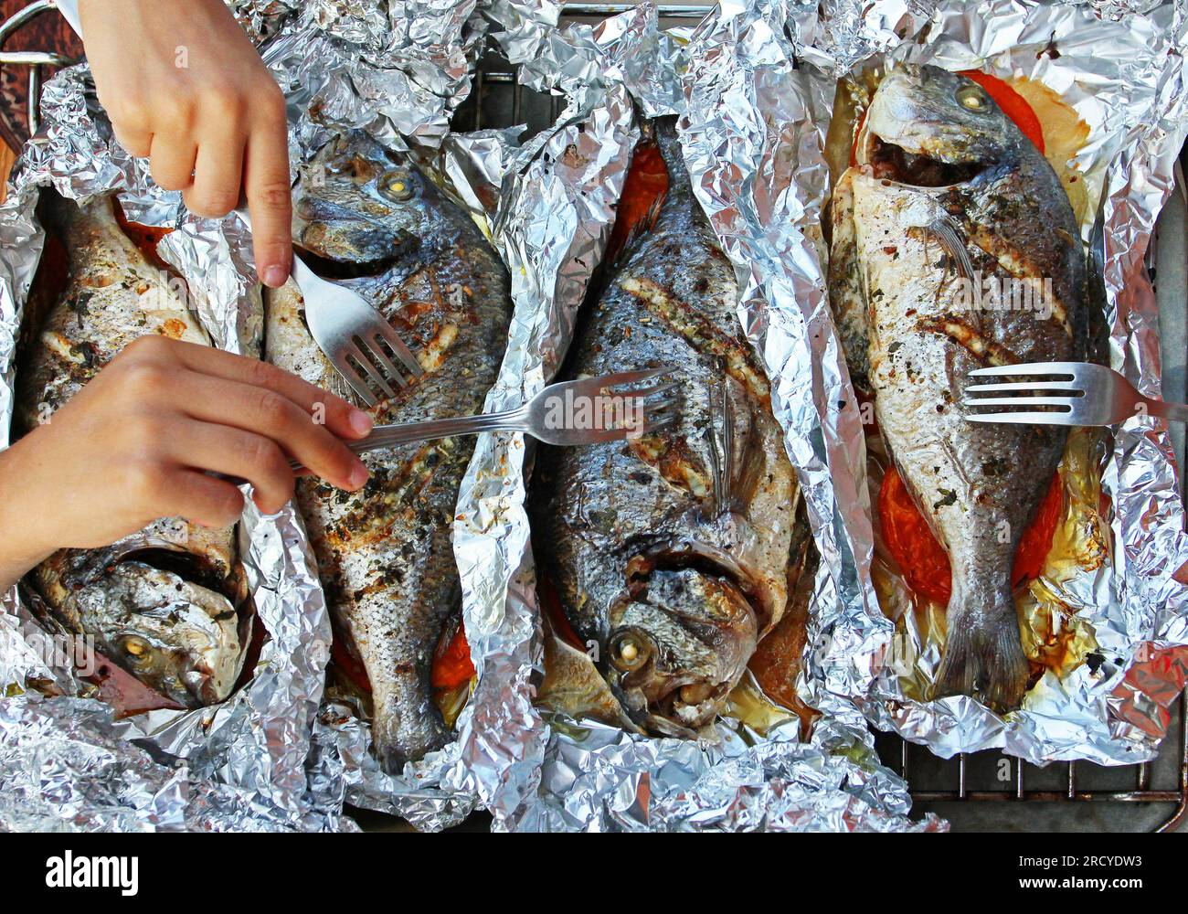 four baked dorado fish in foil with vegetables for a family holiday ...