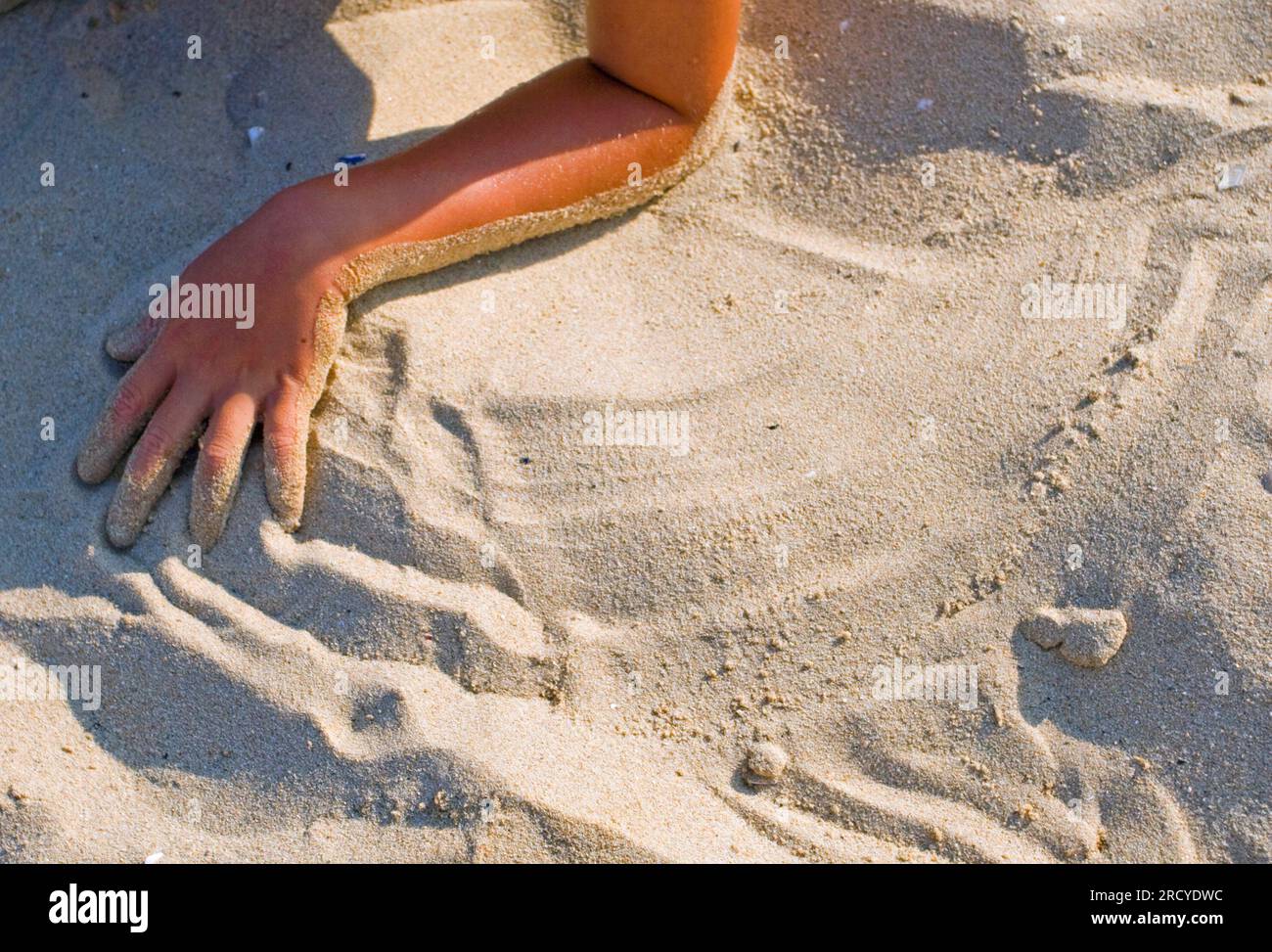 children's tanned hand on the beach smoothes the beach sand on the ...