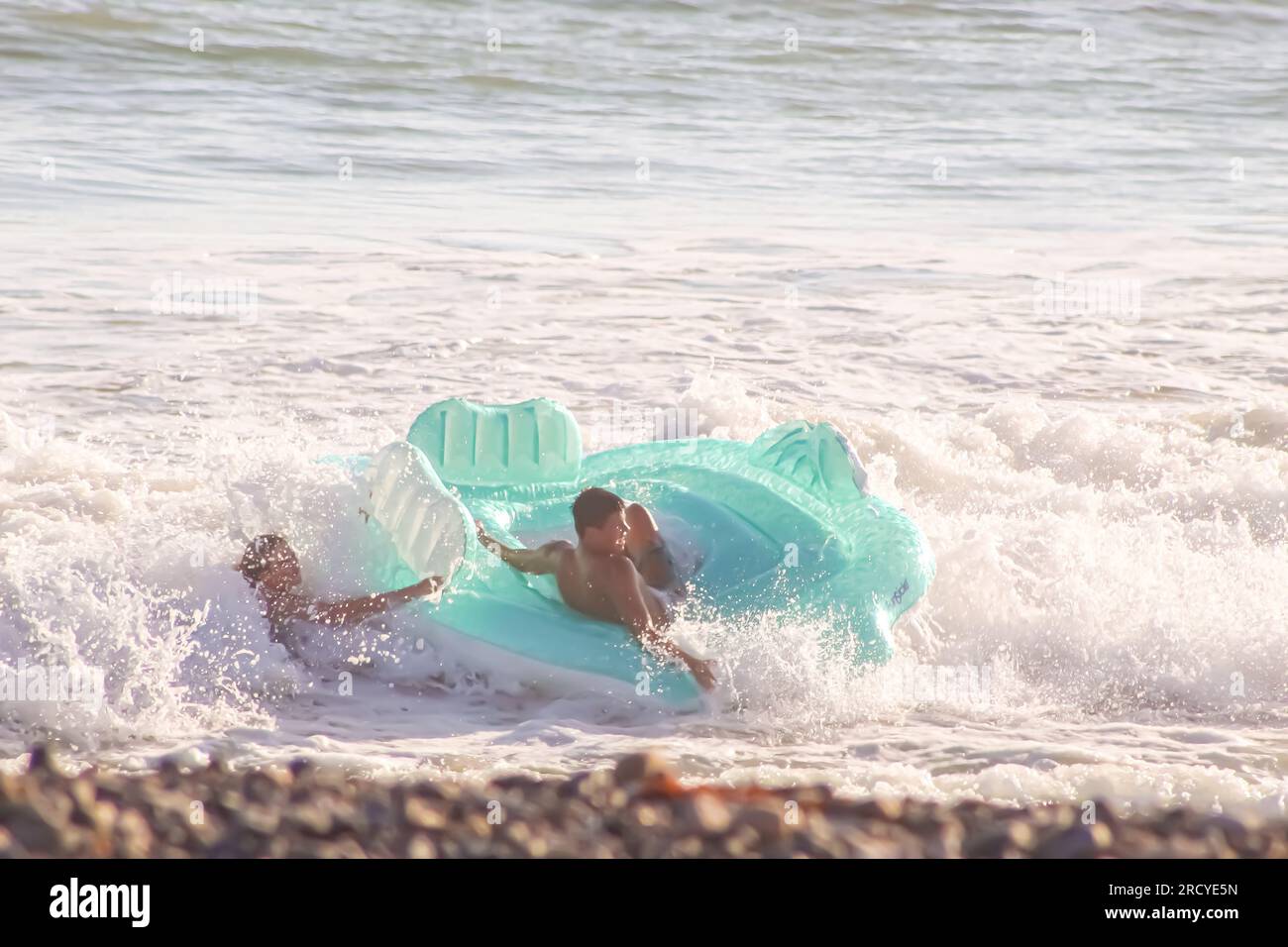 Two Teens Falling off Inflatable in Ocean Stock Photo - Alamy