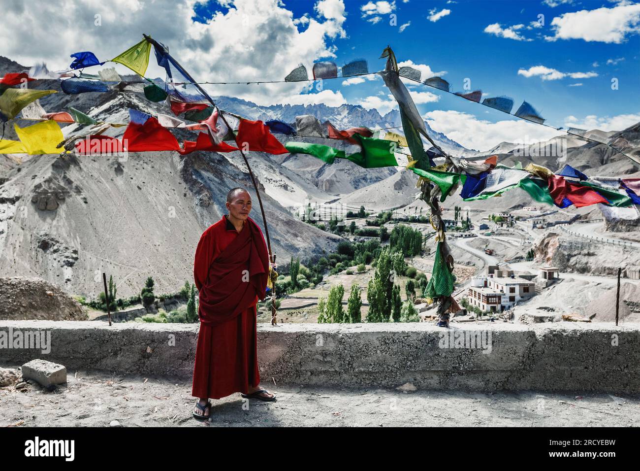 Buddhist monk standing outside with lugta prayer flags in Lamayuru ...