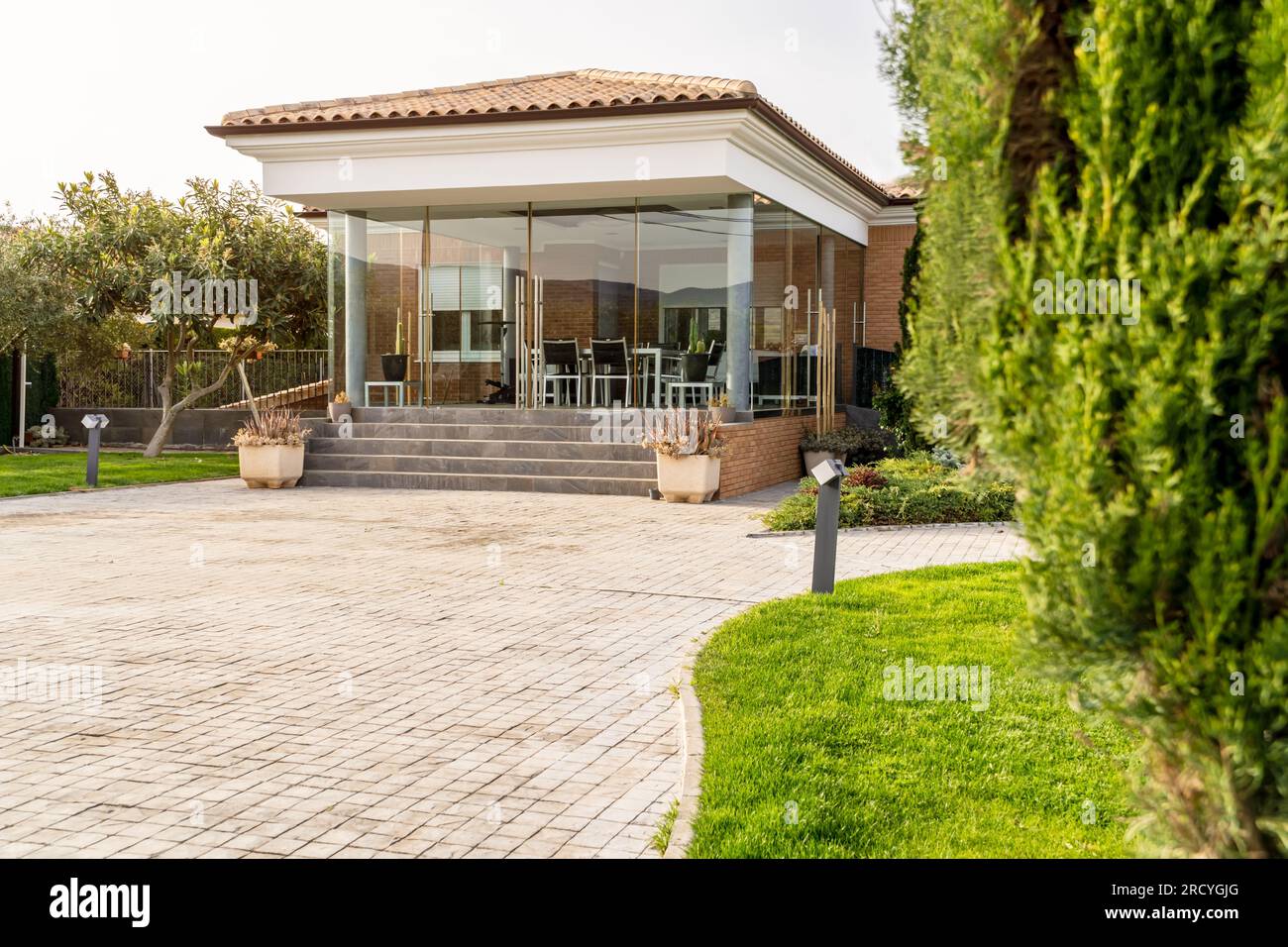 Front view of a private house entry with porch and garden with trees ...
