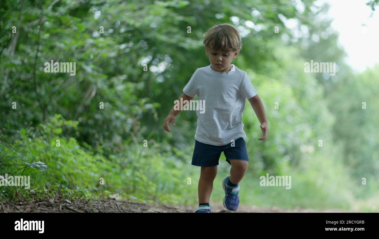 Child walking outside in nature little boy walks outdoors in green path ...