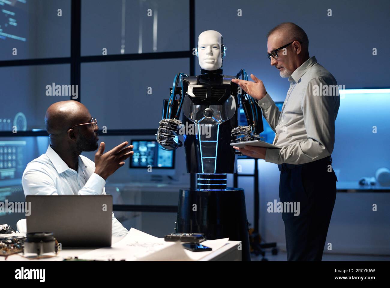 Engineers discussing designing of robot in team during their work in ...