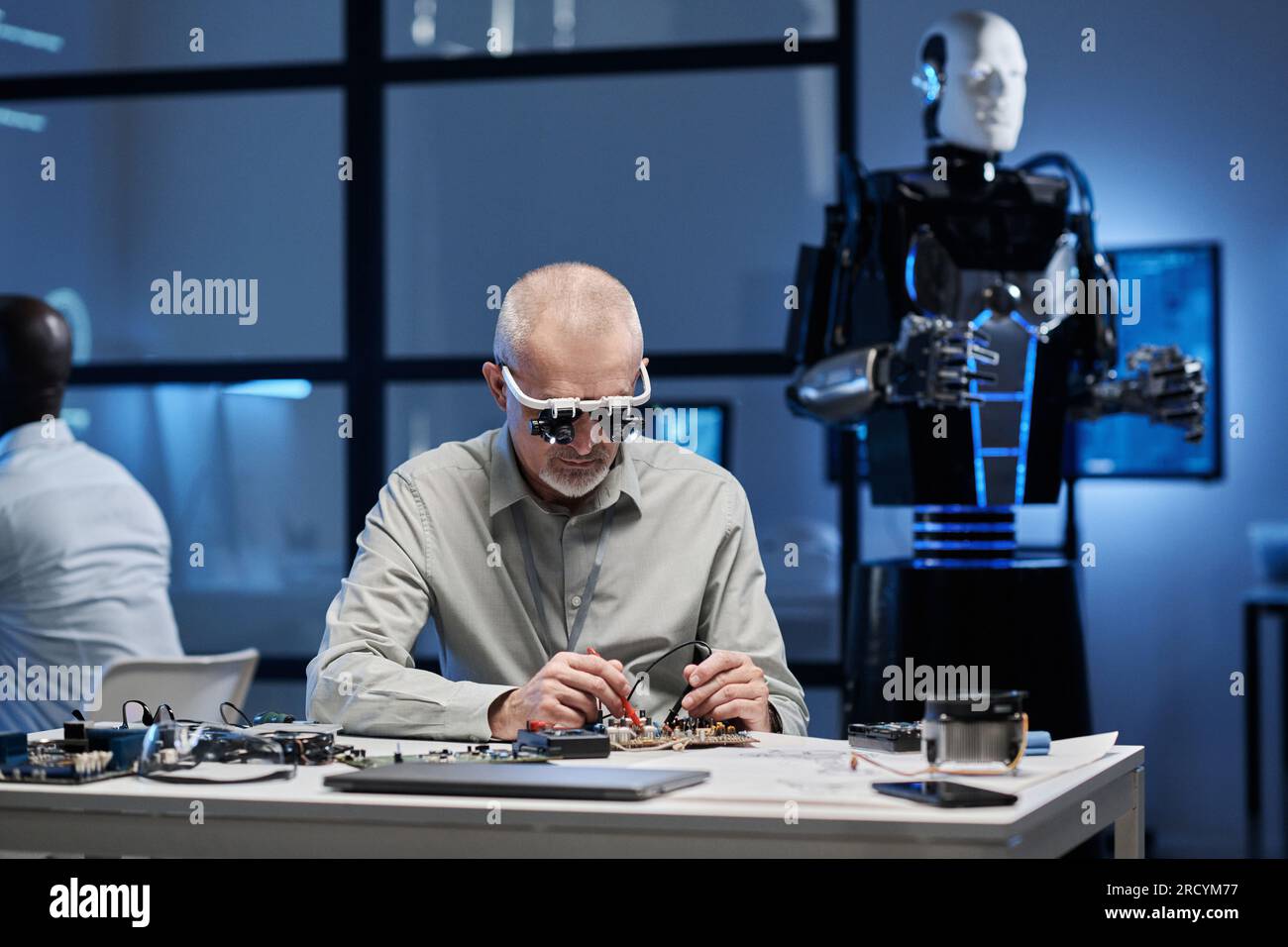 Mature engineer working with motherboard for development of robot in ...