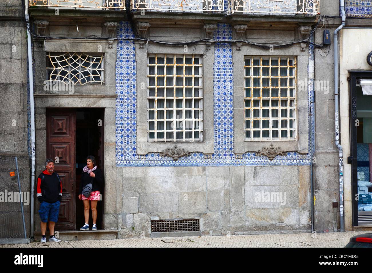 Tourists sheltering from the rain in doorway of typical old house next ...