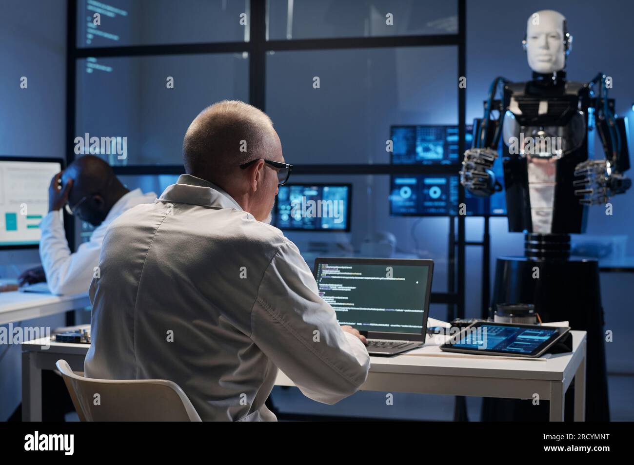 Rear view of mature developer writing codes on laptop for developing ...