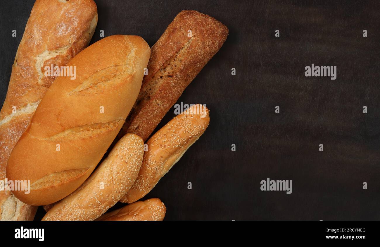 Long loaf on the table, top view. Baton, baguettes and buns with sesame ...