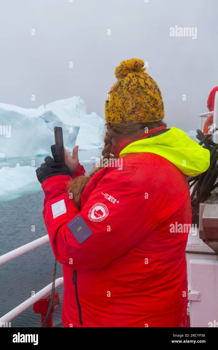 Tourist wearing red jacket on board boat at Ilimanaq, Disko Bay ...