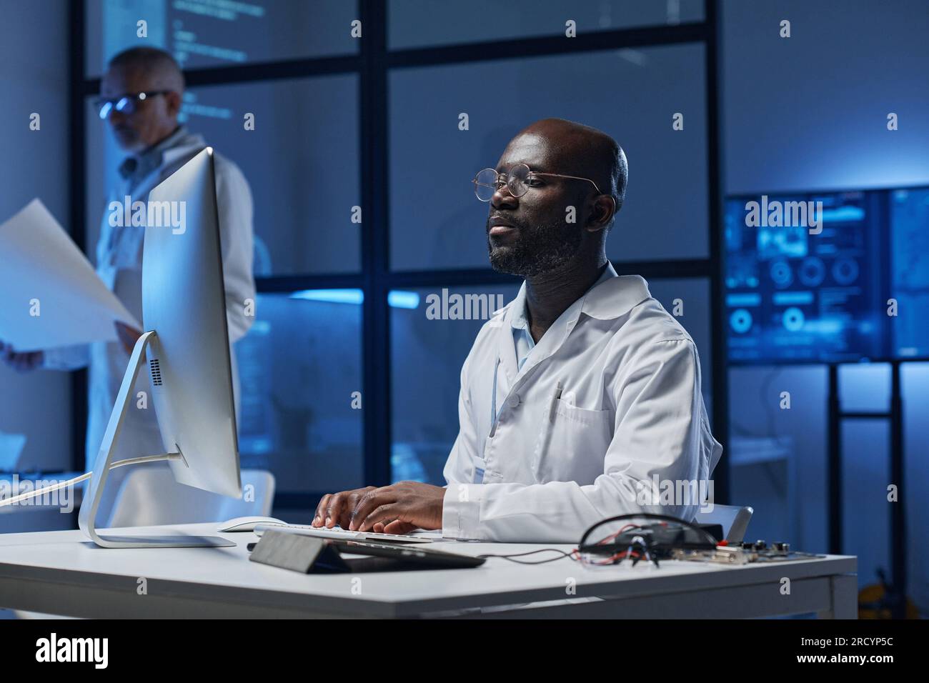 Serious African American engineer working with computer program on ...