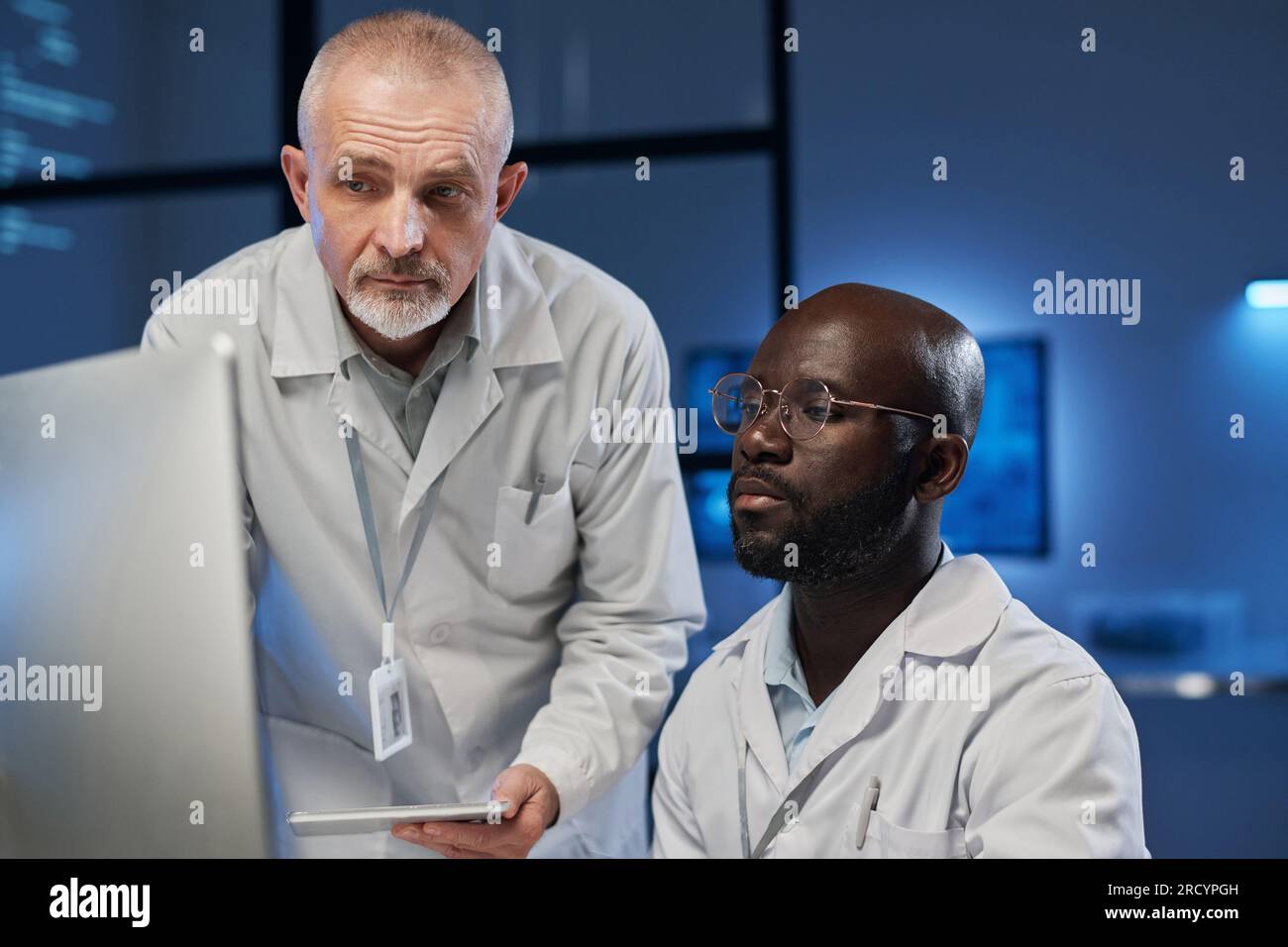 Two multiethnic engineers discussing computer program on computer while ...
