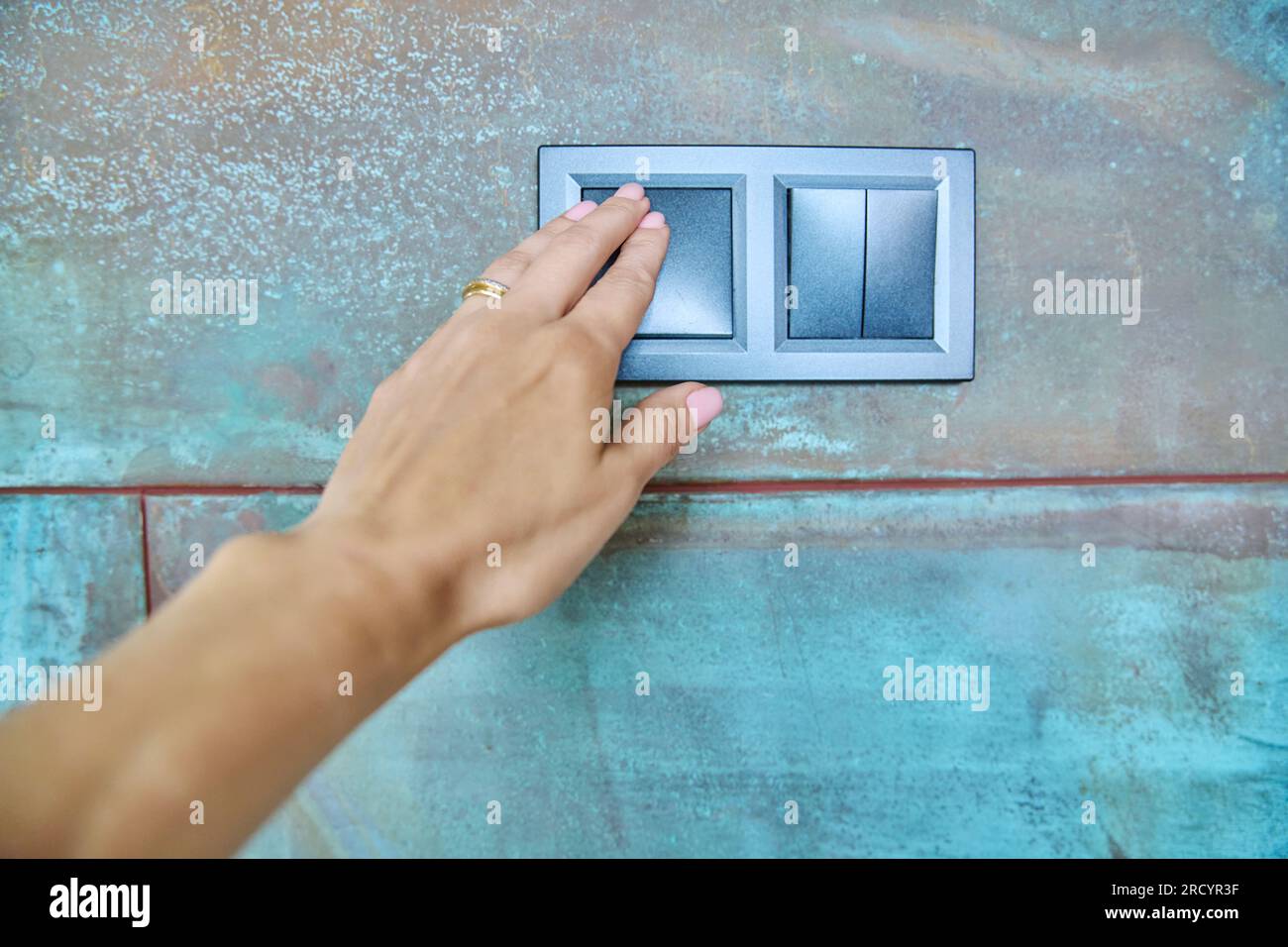 Modern black electrical switch on a wall, woman's hand touches the ...