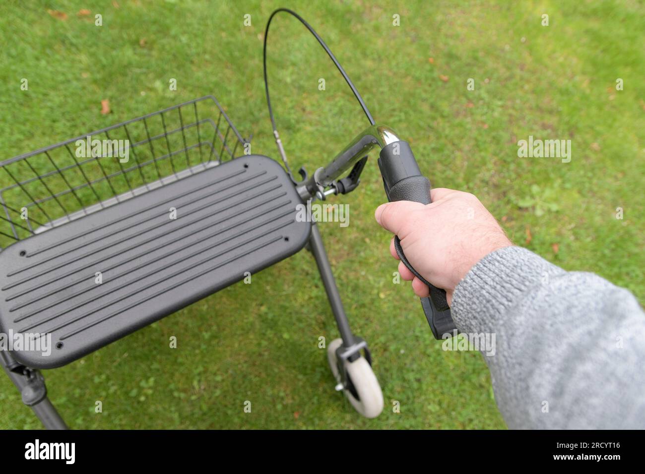A man holding on to the left handle of a rollator. Using Walker ...