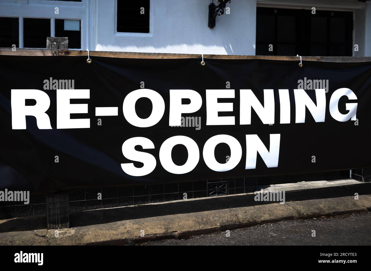 A large sign printed on plastic sheeting reading "Re-opening soon ...