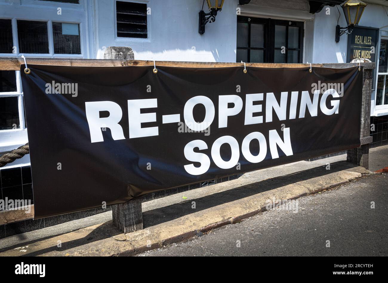 A large sign printed on plastic sheeting reading "Re-opening soon ...