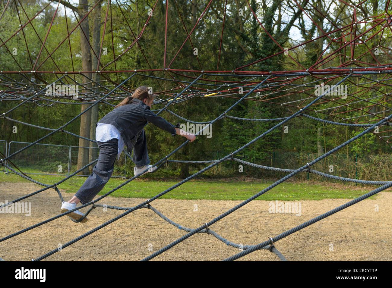 A teen girl climbing on spider web with expression Stock Photo - Alamy
