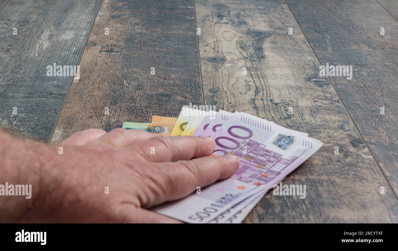 European money cash. The hand on large euro banknotes amount. Wooden ...