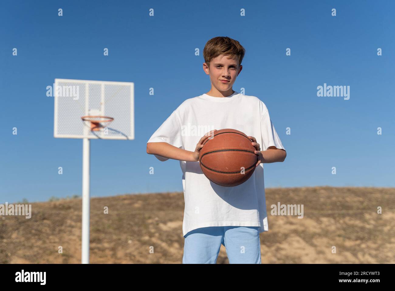 Teenage boy with basketball on a basketball court holding the ball with ...