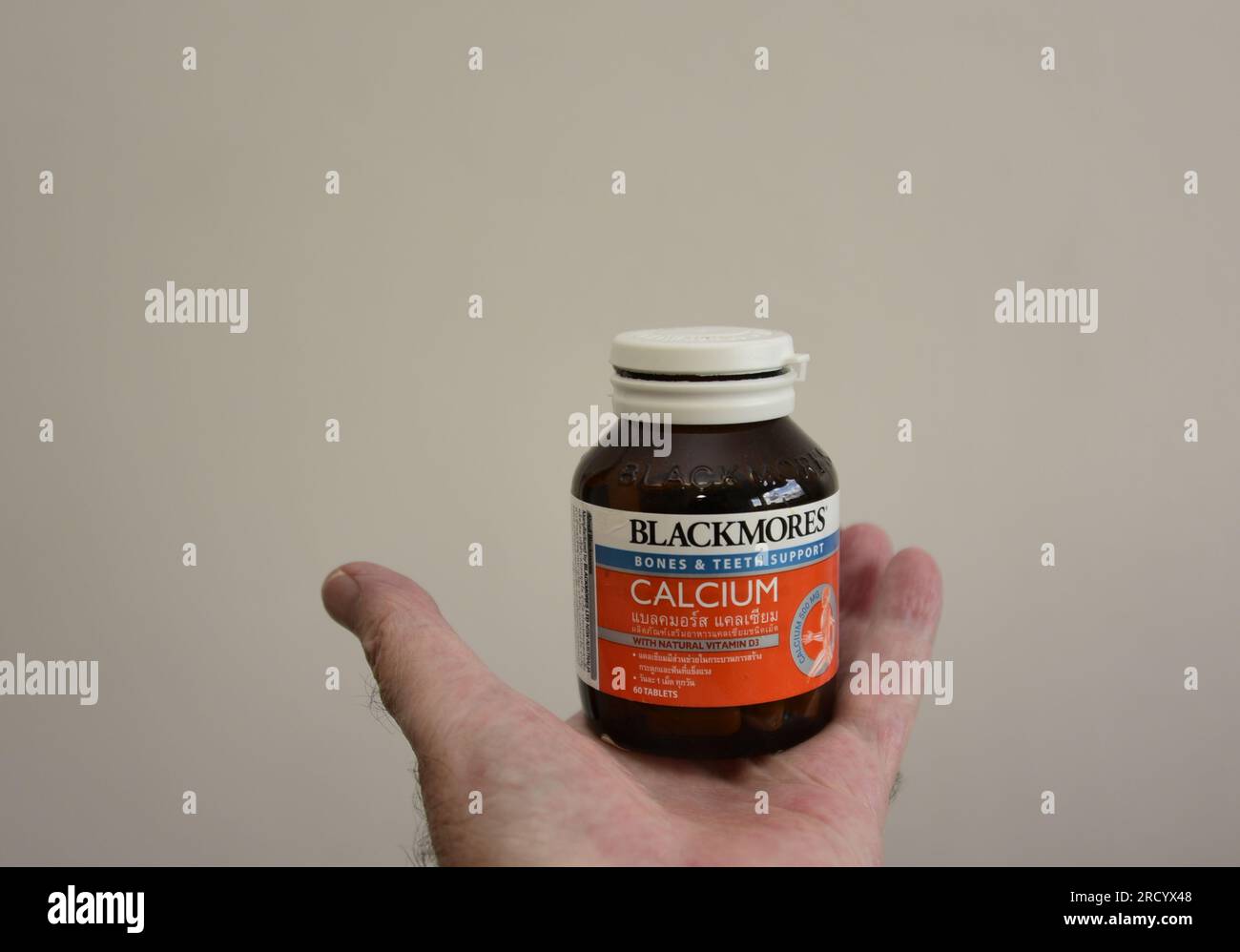 A Caucasian man's left hand holds a bottle of Blackmores brand calcium ...