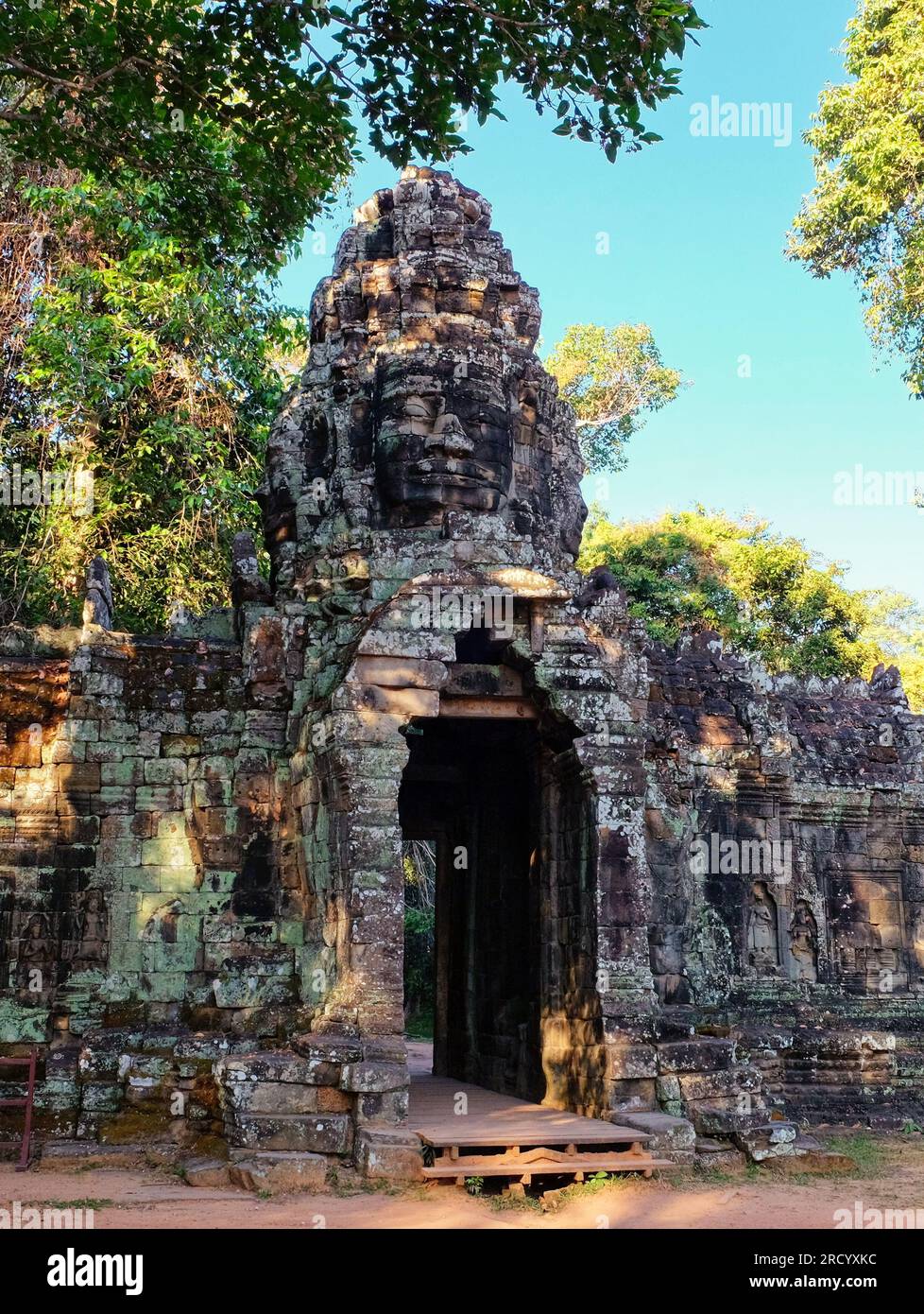 A high stone arch with a tower decorated with images of human faces ...