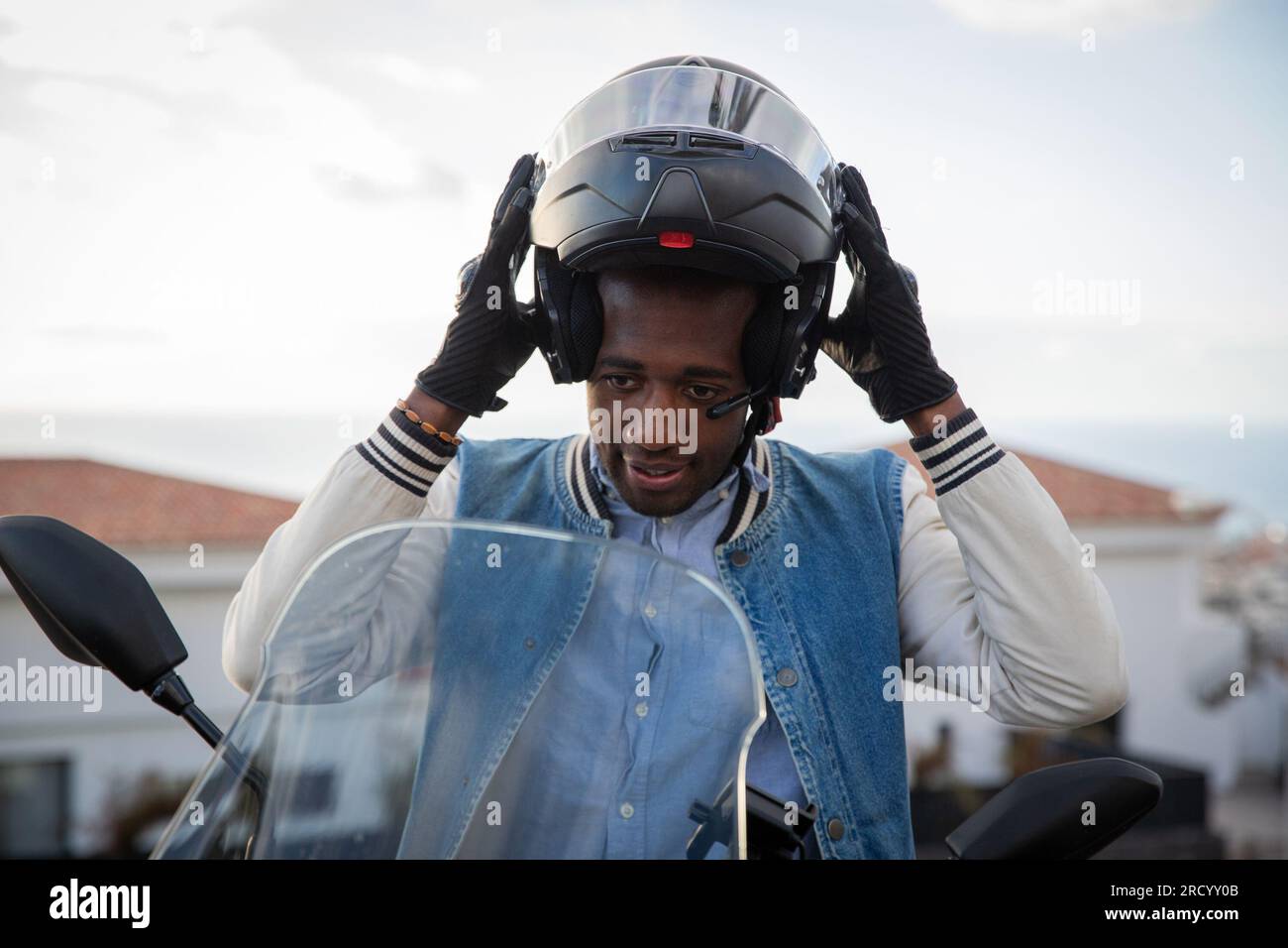 A motorcyclist puts on his helmet before driving his motorcycle, road ...