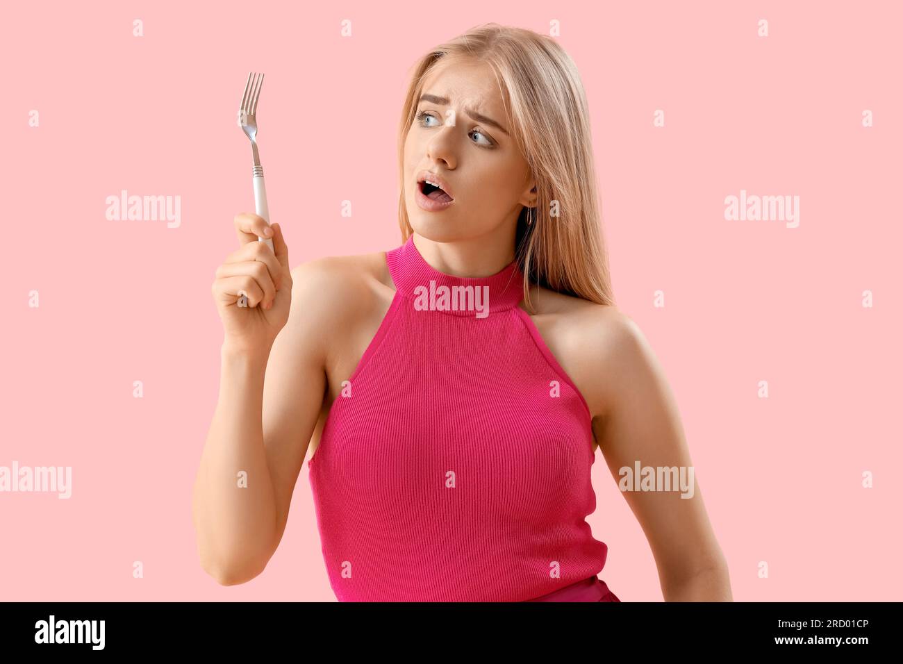 Shocked young woman with fork on pink background Stock Photo - Alamy