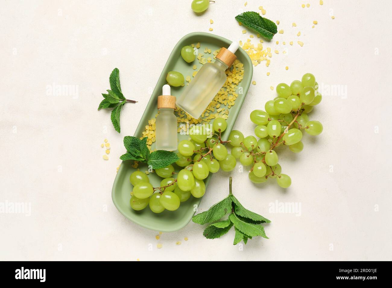 Bottles with cosmetic oil, sea salt and grapes on white background ...