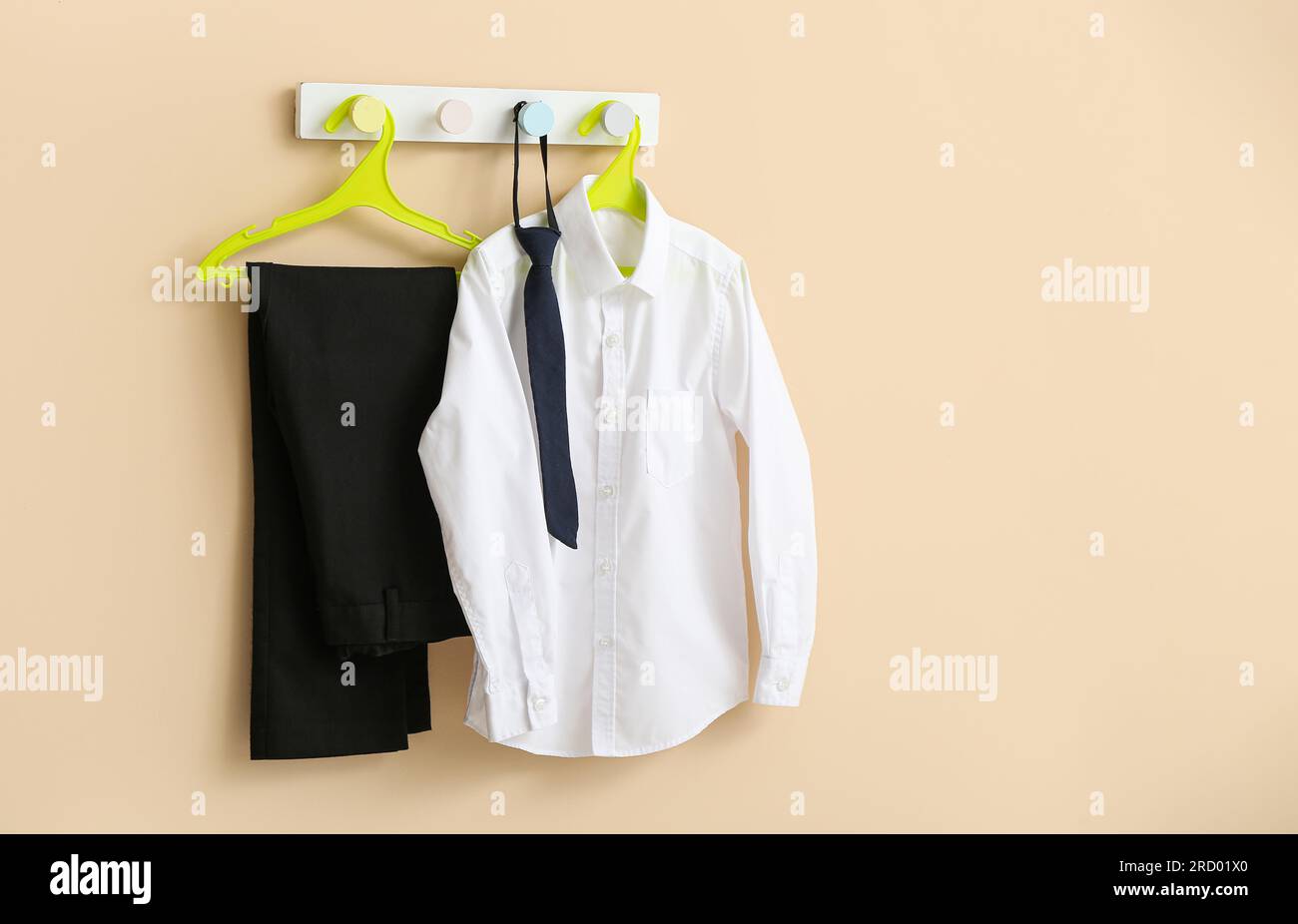 Stylish school uniform hanging on rack against beige wall Stock Photo ...
