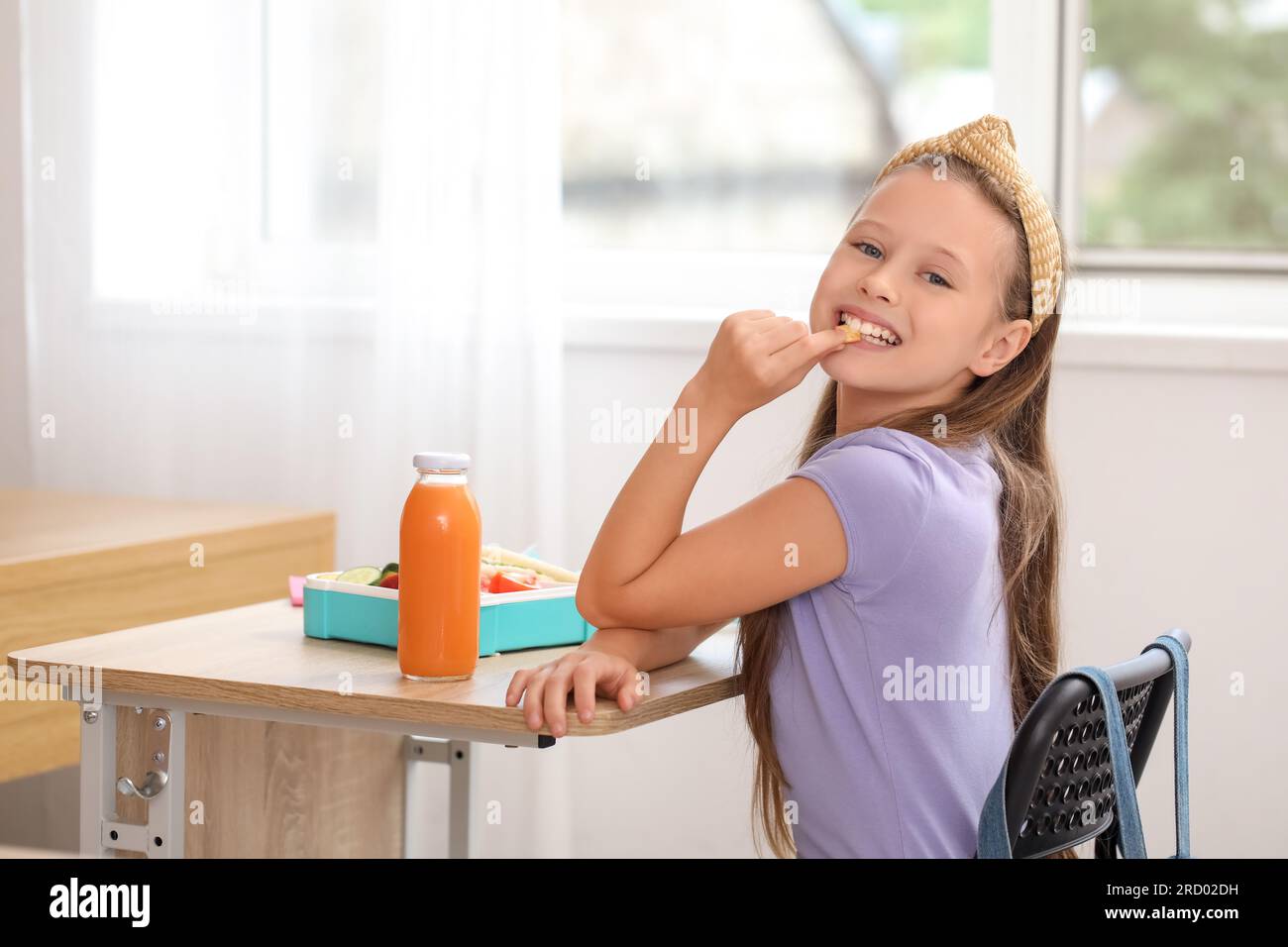 Little girl eating lunch in classroom Stock Photo - Alamy