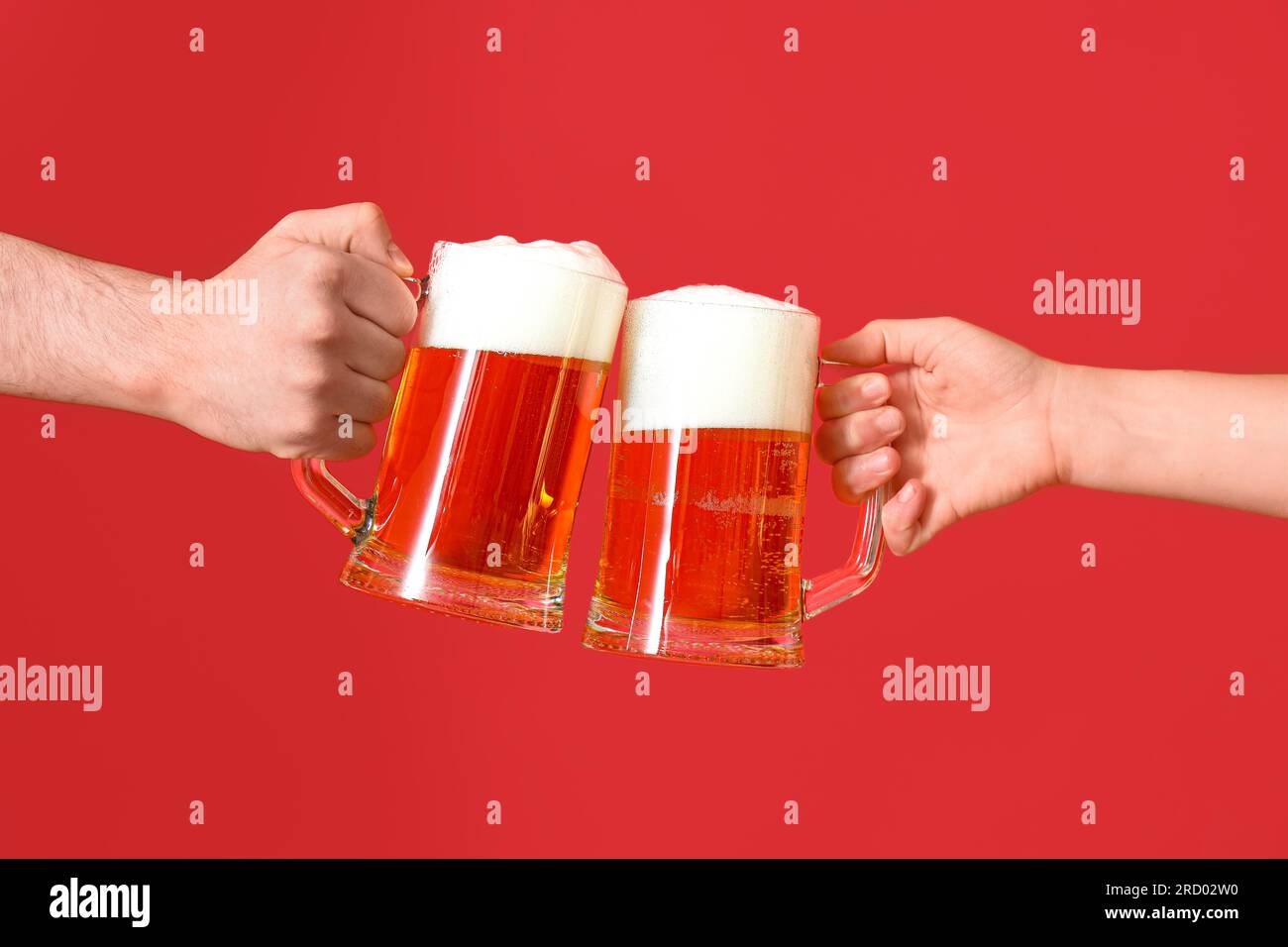 Man and woman with mugs of cold beer clinking on red background Stock ...