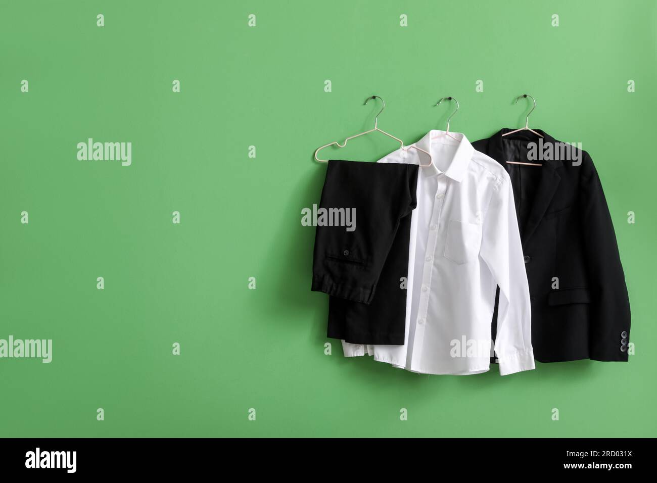 Stylish school uniform hanging on green wall in room Stock Photo - Alamy