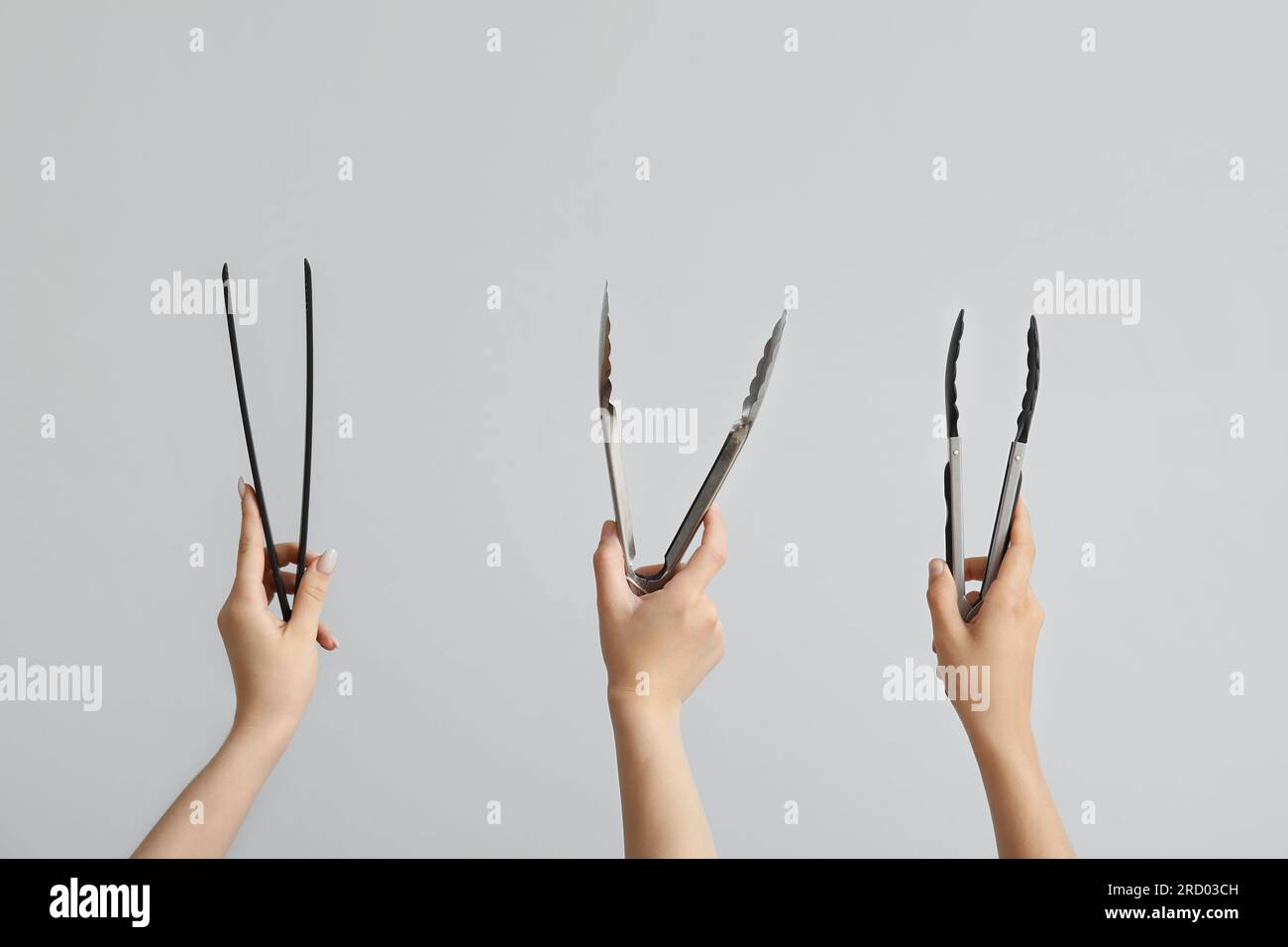 Female hands with tongs on grey background Stock Photo - Alamy