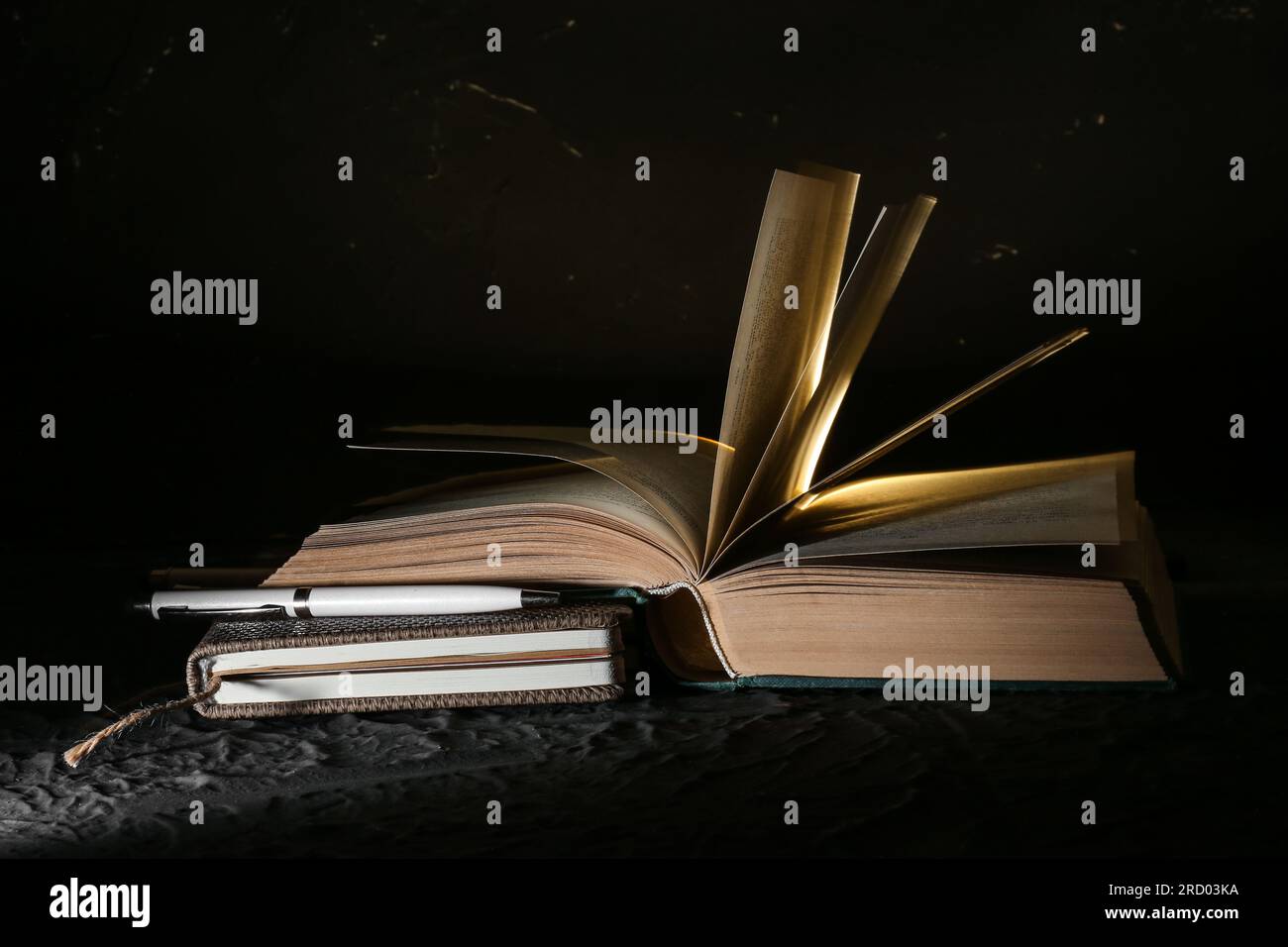 Book with glowing light on black background Stock Photo - Alamy