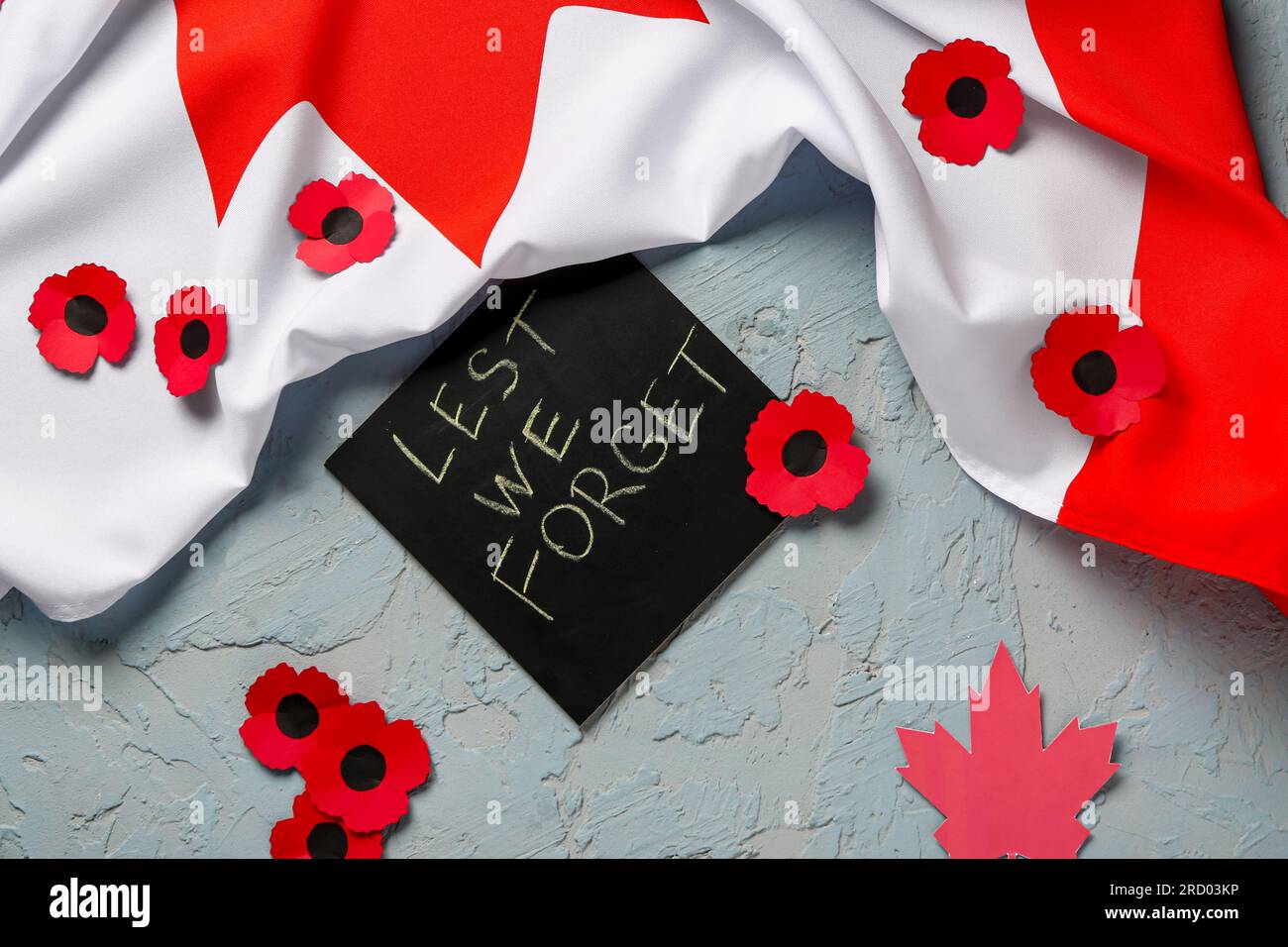 Poppy flowers with flag of Canada and card on textured grey background ...