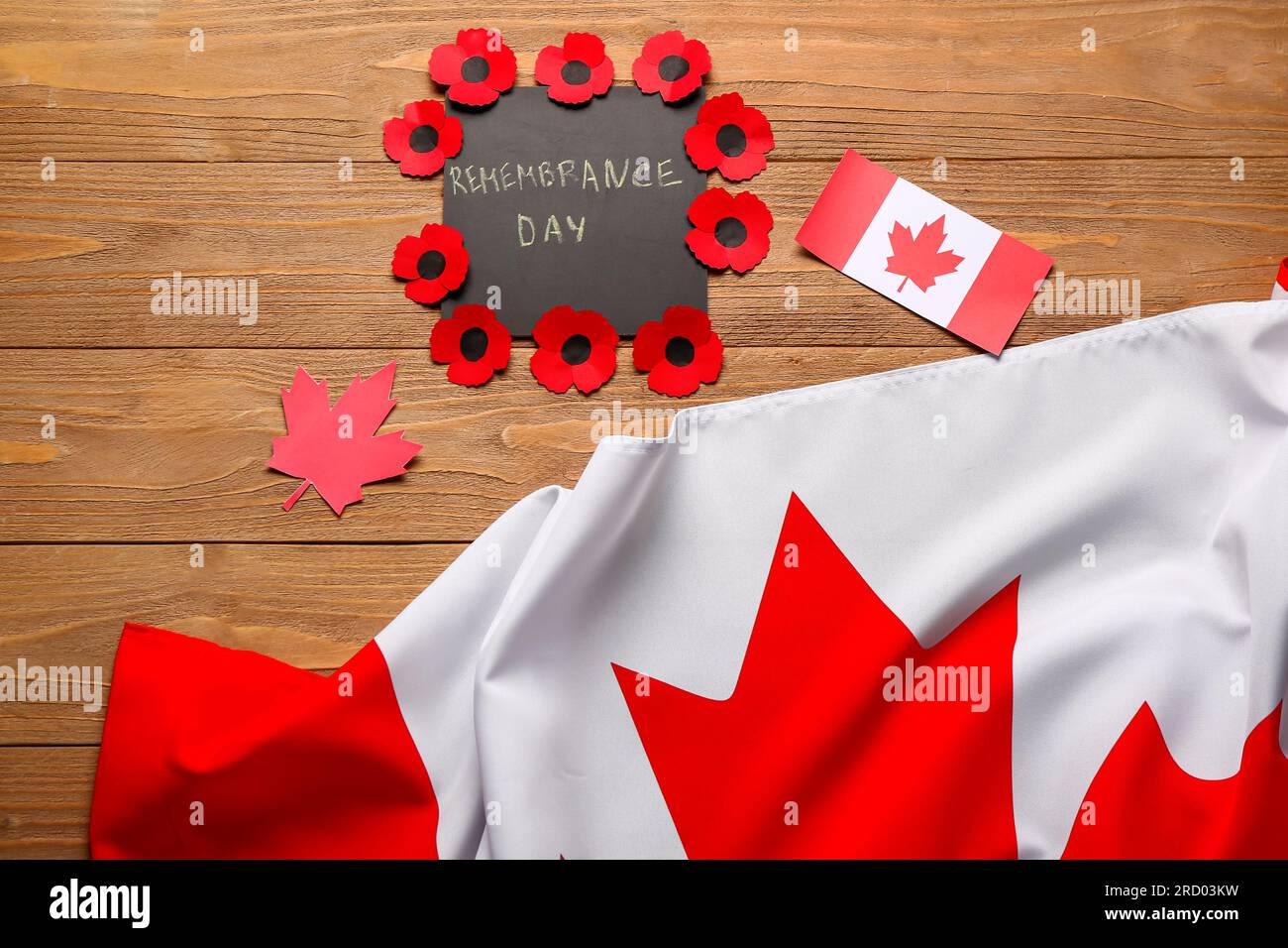Poppy flowers with flags of Canada and card on wooden background ...