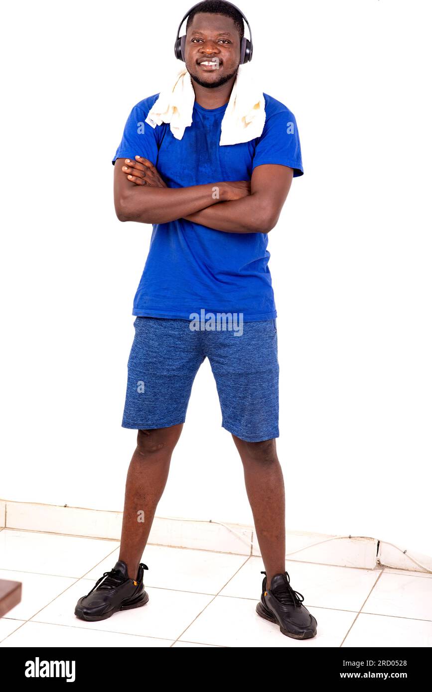young man with crossed arms, towel around his neck standing in a room ...
