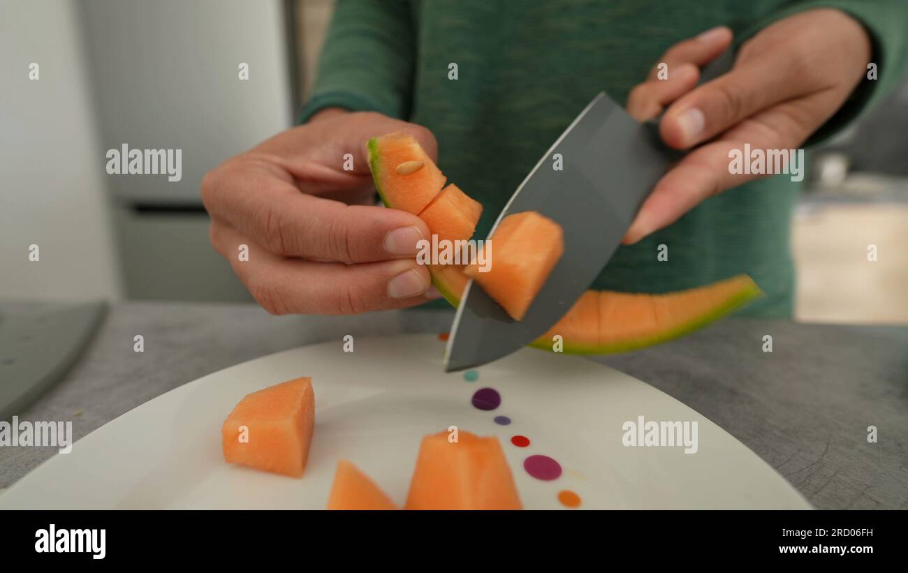 Hand cutting melon in pieces person cuts fruit Stock Photo - Alamy