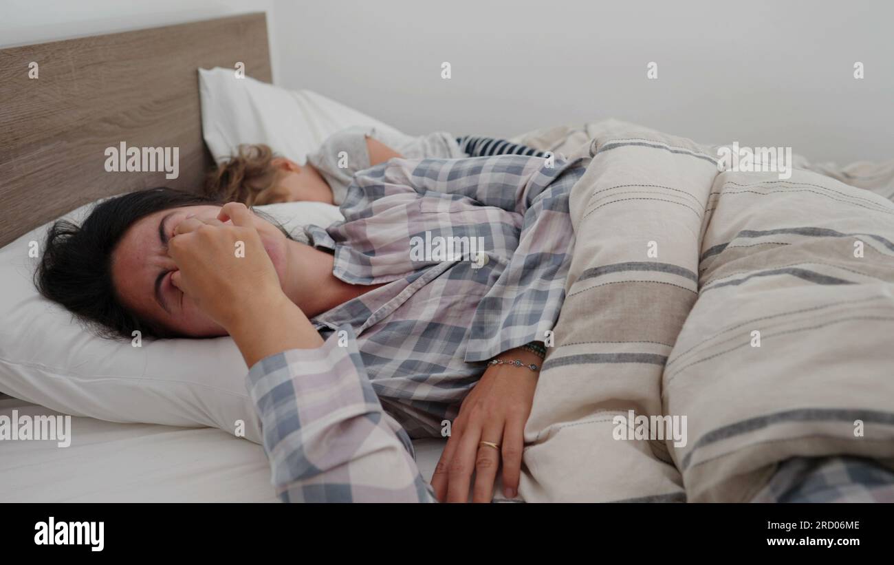 Mother in bed with child waking up in the morning yawning starting the ...